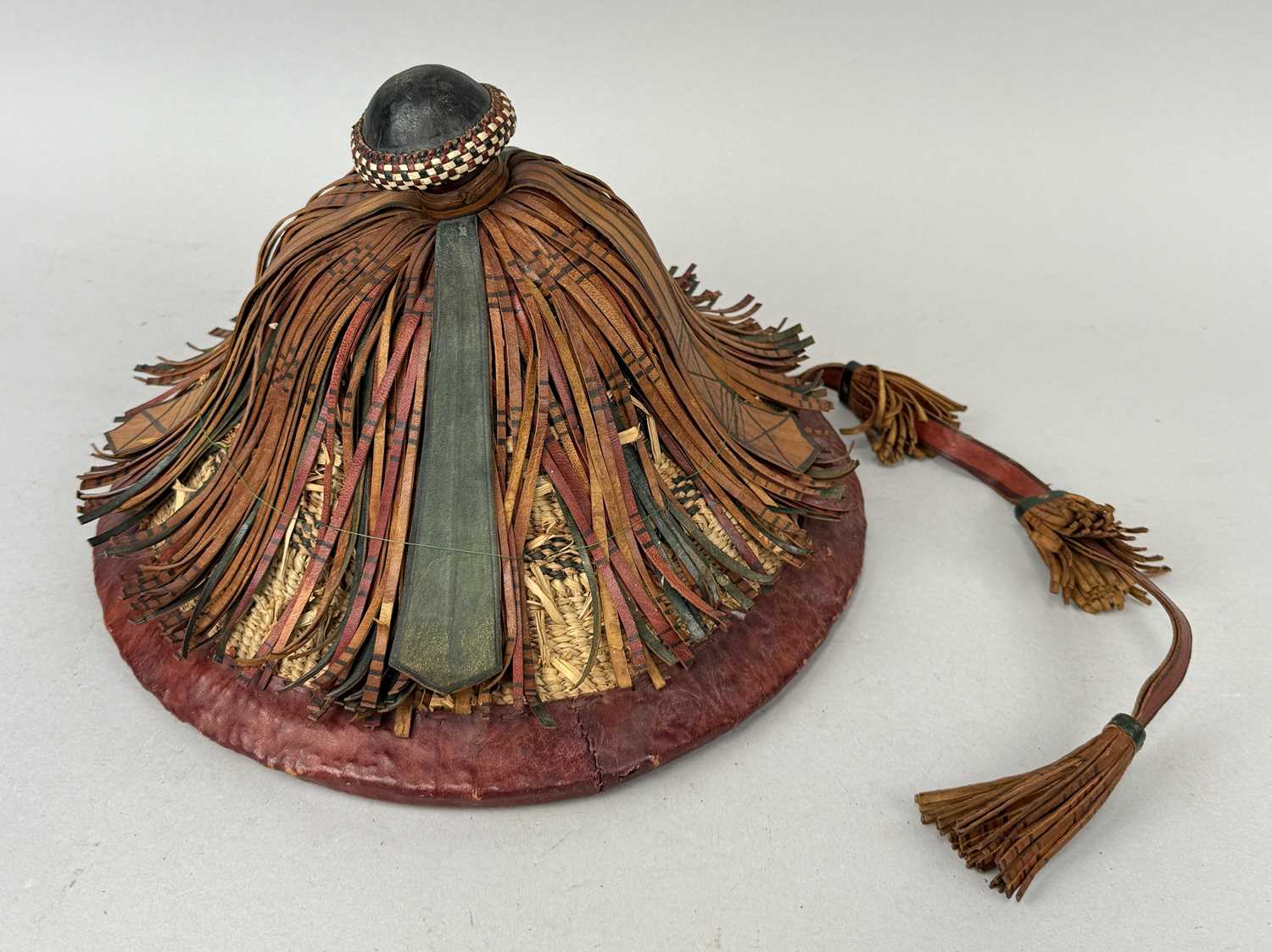 Lot 99 - AN AFRICAN TRIBAL LEATHER-CLAD MAN'S HAT,